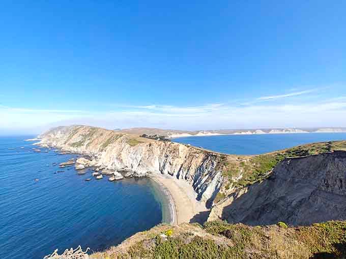 Dramatic coastal cliffs reveal geological history in colorful layers while tide pools sparkle with purple stars and orange anemones.