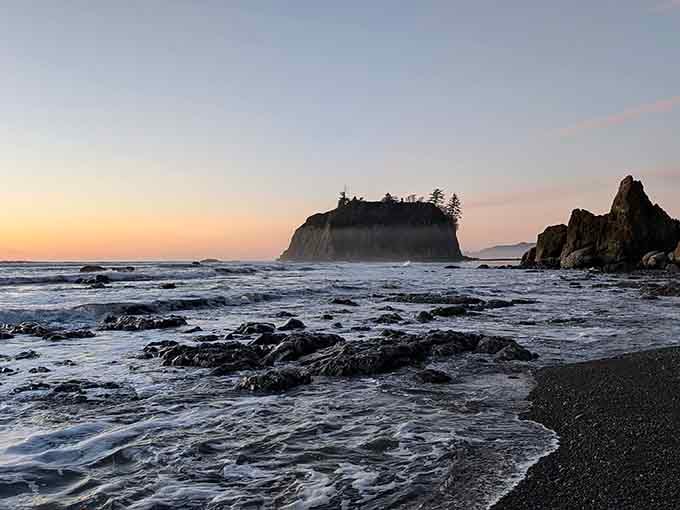 Twilight paints the rocky coastline in pastels while waves whisper secrets to the driftwood-strewn shore.