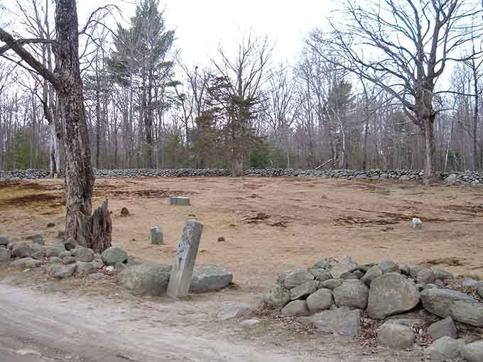 Ancient headstones lean at odd angles within the rock-lined perimeter, creating shadows that play tricks on your imagination.