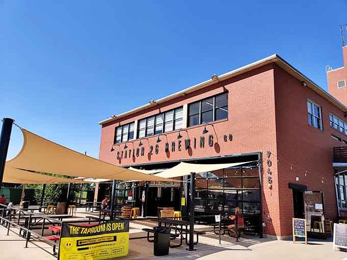 The taproom sign beckons under golden shade sails where neighbors gather for fresh-brewed craft beer and easy conversation.