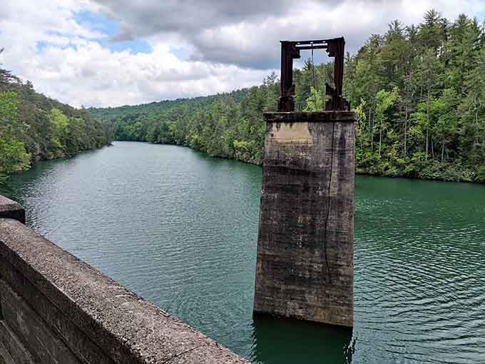 The old dam structure stands sentinel over emerald waters, a reminder of engineering meeting raw natural beauty perfectly.
