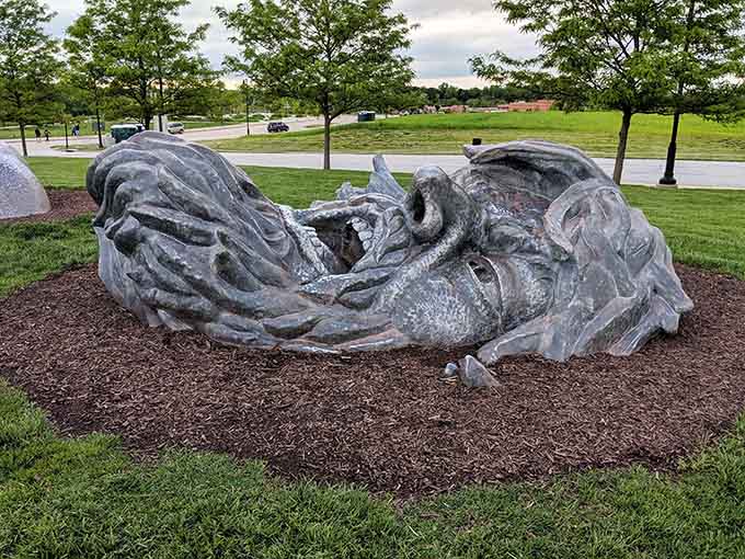 The giant's weathered face emerges from the earth, frozen mid-struggle in this dramatic and unforgettable sculpture.