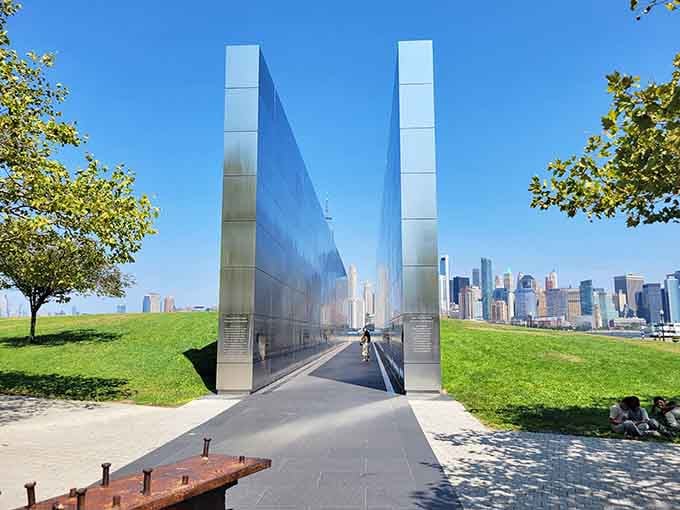The reflective memorial catches clouds and sky, offering a quiet space for contemplation with the city beyond.