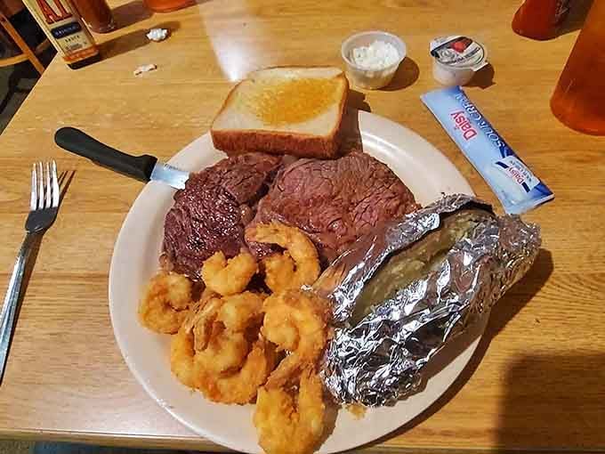 Surf meets turf in glorious harmony: a perfectly seared ribeye sharing space with golden fried shrimp and foil-wrapped potato.