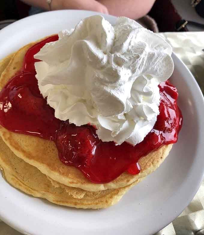 Strawberries and whipped cream on pancakes&mdash;because sometimes adulting means ordering dessert for breakfast and nobody can stop you.