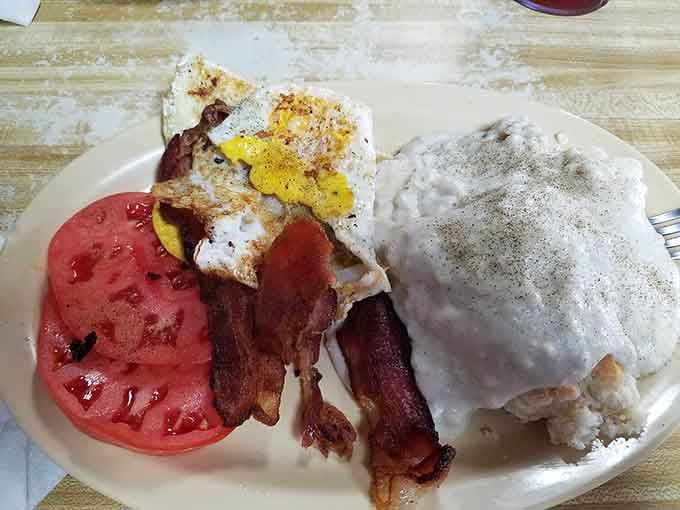 Eggs, bacon, biscuits drowning in gravy, and a tomato slice trying its best to make this look healthy.