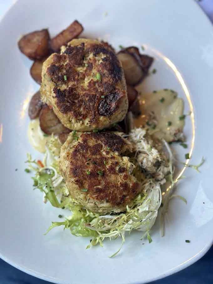 Golden-crusted perfection sitting pretty on a bed of greens, proving crab cakes can indeed be works of edible art.