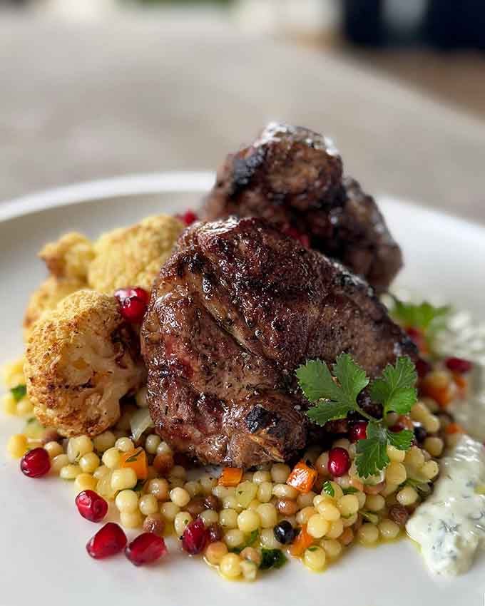 Lamb chops over jeweled couscous look like they belong in a museum, taste like pure heaven.