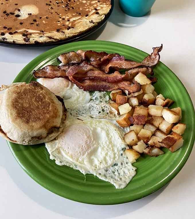 Perfectly cooked eggs, crispy bacon strips, and golden home fries on a sunny yellow plate scream weekend victory.