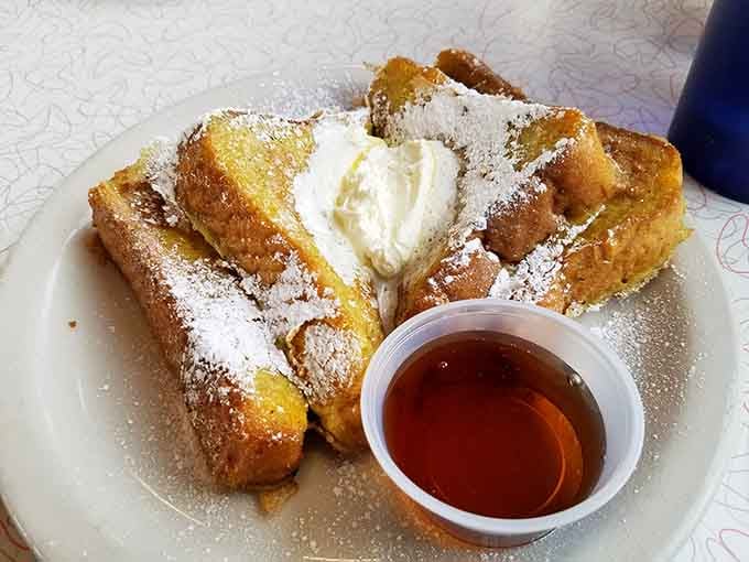 French toast dusted with powdered sugar and topped with whipped cream, sweet morning perfection on a plate.