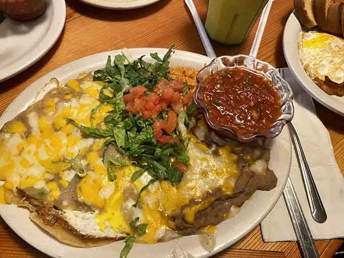 Huevos Rancheros topped with enough cheese, salsa, and greens to make your taste buds stand up and salute.