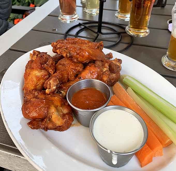 Crispy wings with celery, carrots, and dipping sauces arranged like they're posing for their yearbook photo.