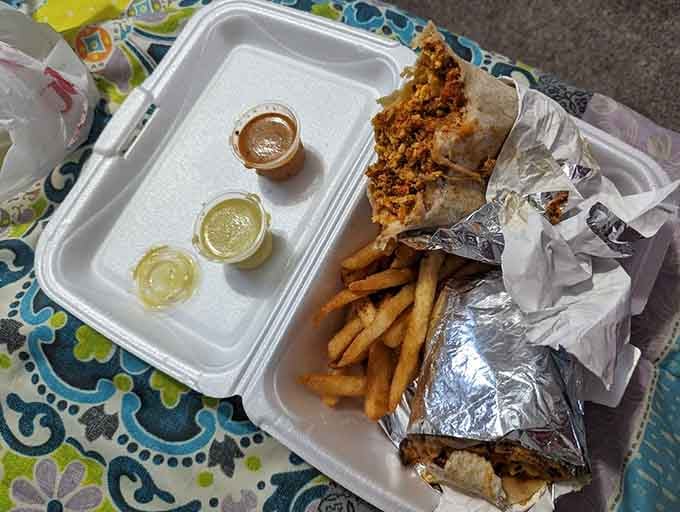 A breakfast burrito wrapped in foil with fries and salsa: because sometimes the best mornings start at a gas station.