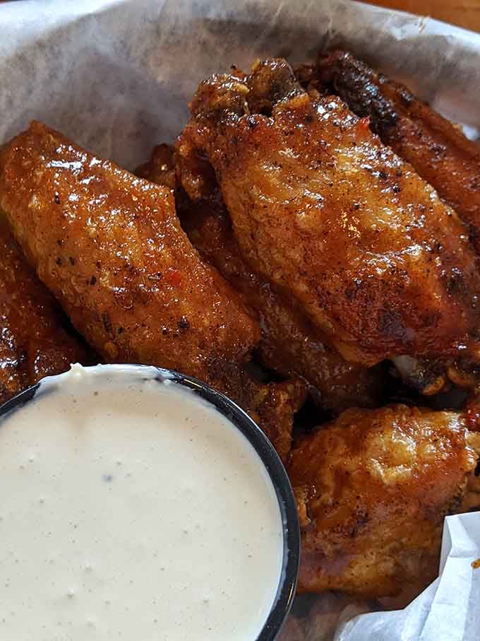 Those house-smoked wings glisten with sauce like they've been kissed by flavor angels, ranch dressing standing by for duty.
