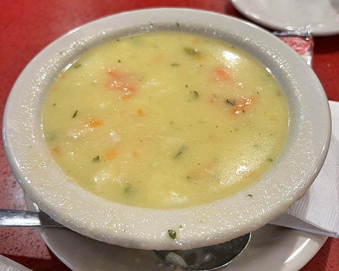 Golden chicken soup that looks like liquid sunshine decided to become comfort food, complete with vegetables swimming in pure happiness.