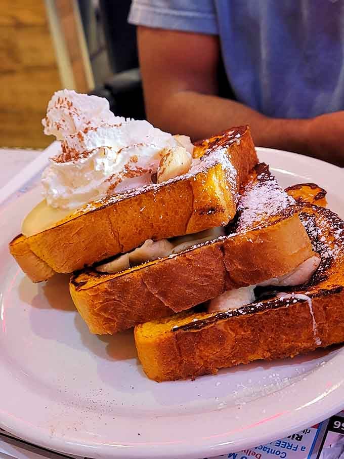 French toast stacked high with whipped cream, because sometimes breakfast should feel like winning the lottery.