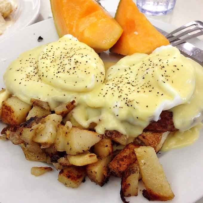 Eggs Benedict draped in hollandaise sauce, proving that some classics never need improvement, just proper execution.
