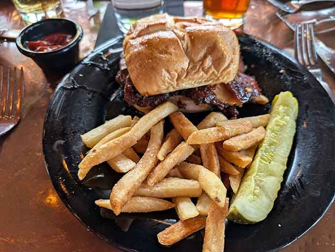 A burger and fries combo that understands the assignment, complete with a pickle spear for good measure.