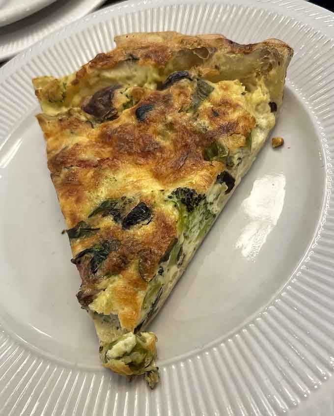 This quiche slice showcases that perfect custard-to-crust ratio that makes French baking an art form worth celebrating.