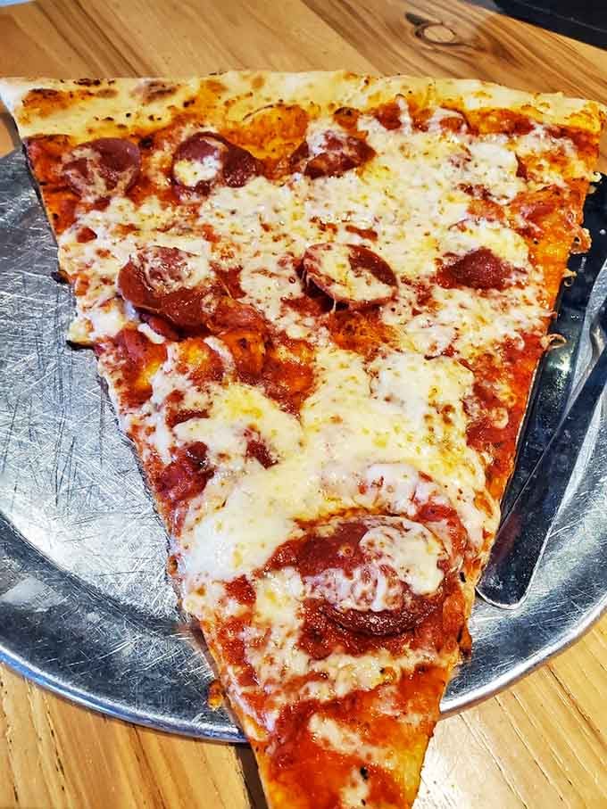 Pepperoni paradise on a slice that requires architectural engineering to hold properly without structural collapse occurring.