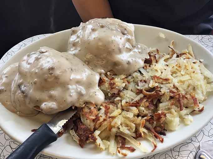 Biscuits drowning in sausage gravy with crispy hash browns, Southern comfort food that transcends all regional boundaries.