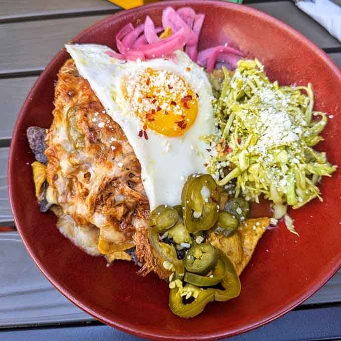 Those perfectly fried eggs crown the chilaquiles like golden jewels, ready to break and create rivers of yolk through every bite.