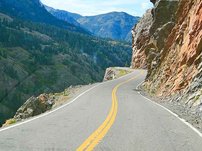 The highway hugs the cliff face tighter than your aunt at Thanksgiving, with considerably more dramatic consequences.