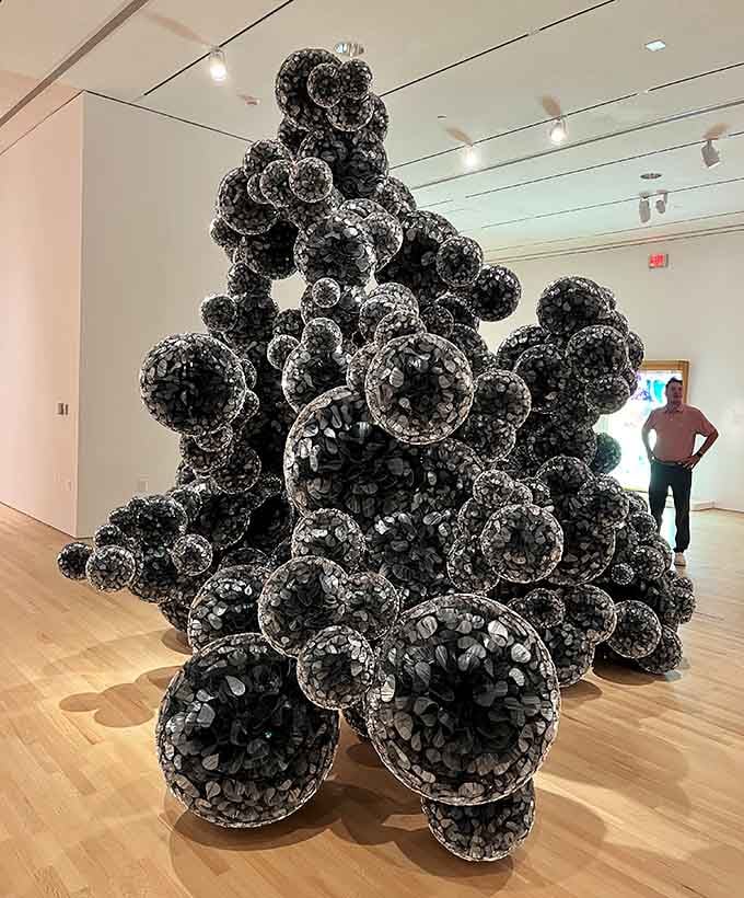Thousands of black spheres cluster together creating an organic sculpture that resembles nature's own architectural experiment.