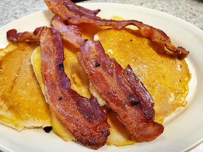 Those bacon strips are so perfectly crispy, they could double as edible architecture on fluffy pancakes.