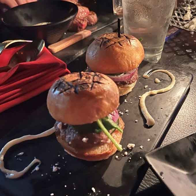 These sliders arrive skewered and ready, proving that even mini burgers deserve a dramatic entrance at Raven's Manor.