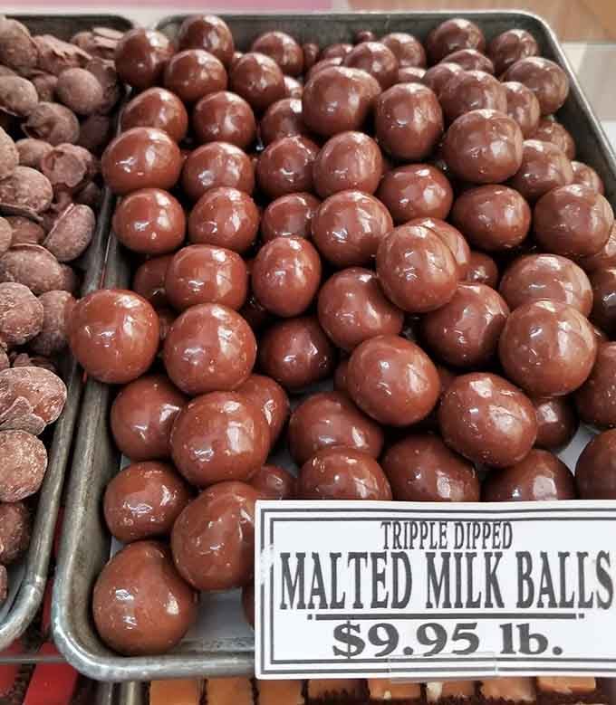 Triple-dipped malted milk balls gleaming like chocolate pearls, each one a three-layer commitment to deliciousness you won't regret.