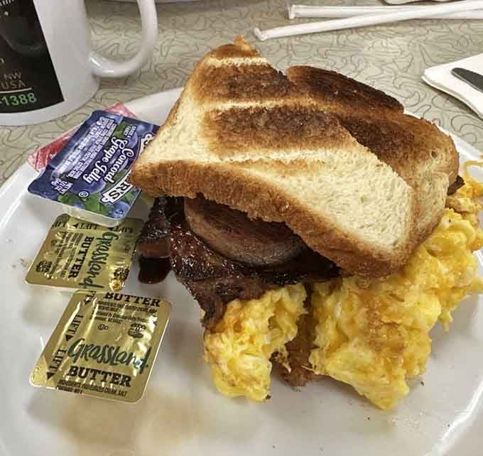 Country ham tucked between toast with scrambled eggs, the kind of sandwich that makes mornings worth experiencing.