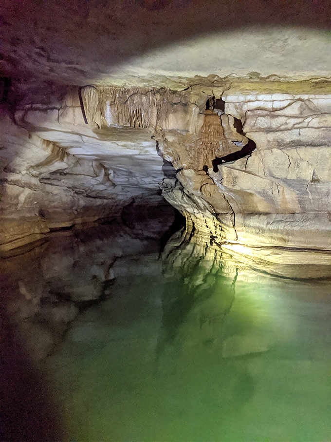 The underground stream glows an otherworldly green, like someone installed mood lighting millions of years ago.