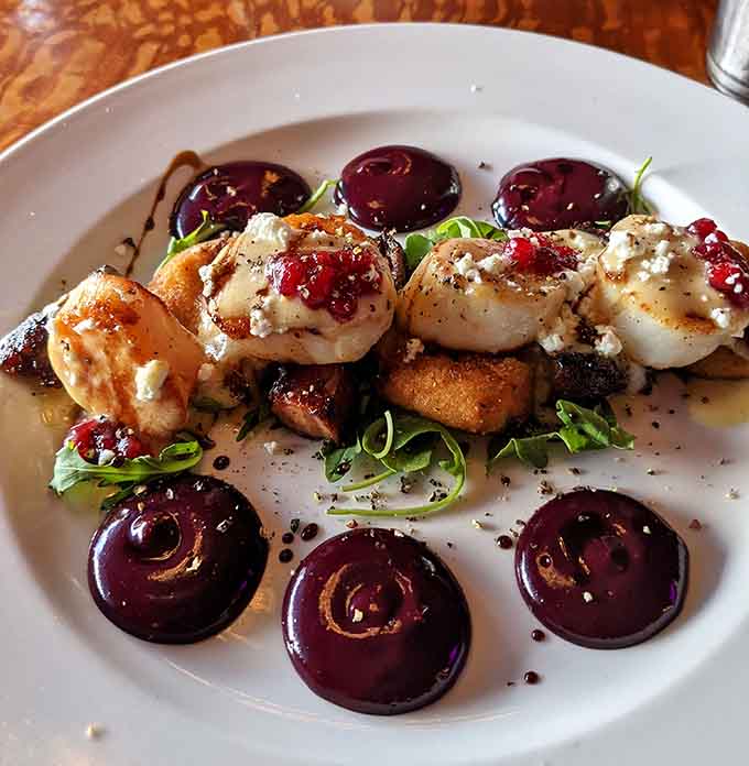 Scallops and pork belly arranged like edible art, surrounded by sauce dots that deserve their own gallery showing.