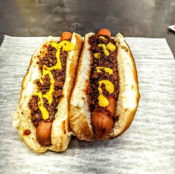 Two chili dogs dressed in mustard and meat sauce, ready to make your taste buds very, very happy.