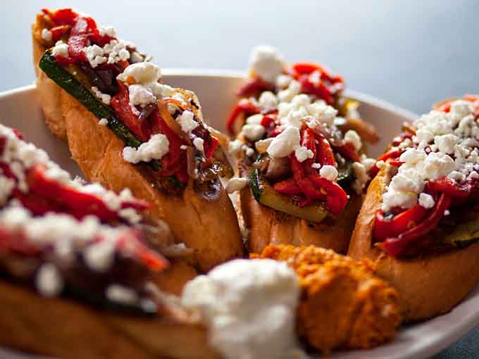 Bruschetta gets the gourmet treatment with roasted vegetables and crumbled cheese that'll transport you straight to flavor town.