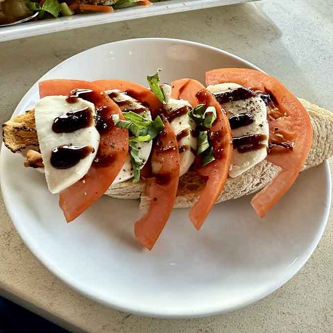 Fresh tomatoes and mozzarella arranged like edible art, drizzled with balsamic that makes everything better in life.