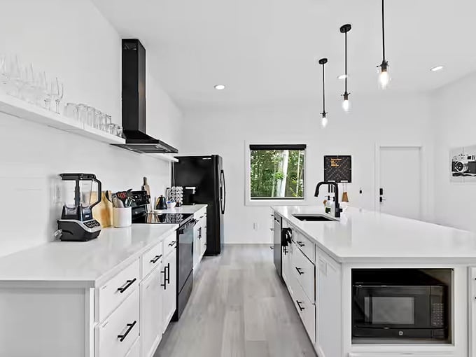 This galley kitchen gleams with white countertops and black accents, perfect for brewing morning coffee before lens-gazing begins.