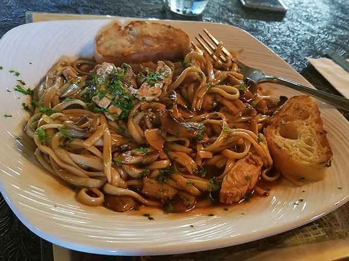 Chicken Marsala arrives with pasta twirled just right, garlic bread standing guard, and mushrooms doing the heavy lifting.