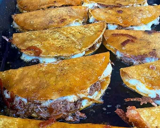 Birria tacos sizzling on the griddle, their golden shells promising the kind of crunch that makes everything right.
