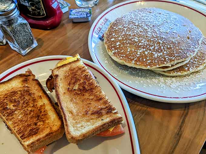 Stack of pancakes meeting a crispy sandwich creates the kind of breakfast spread that makes you want to cancel all your plans.