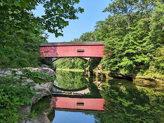 This covered bridge's crimson reflection doubles the charm, creating a postcard moment that practically photographs itself.