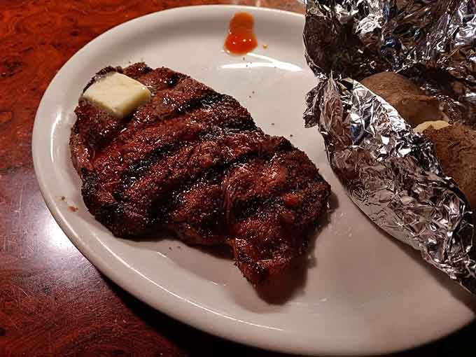 A beautifully charred New York strip with a pat of butter melting on top, pure steakhouse perfection.