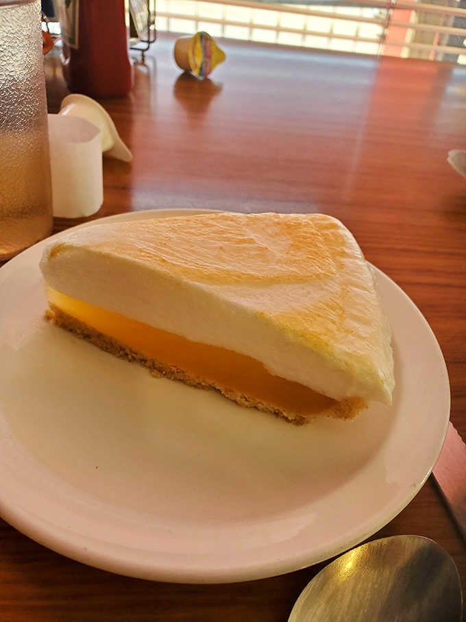 Lemon meringue pie standing tall and proud, ready to deliver sunshine in every single bite.