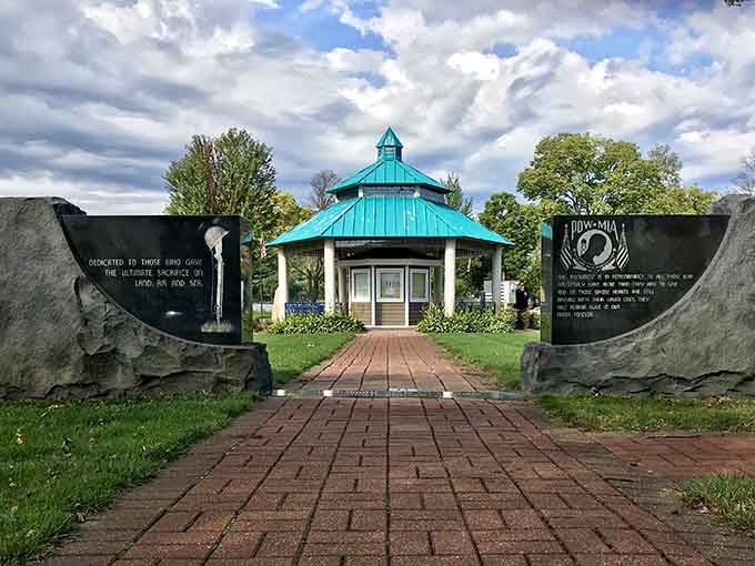 The memorial pavilion stands as a peaceful tribute, its turquoise roof and brick pathway inviting quiet reflection beneath open prairie skies.