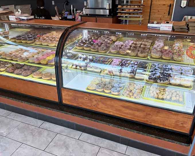 Behold the curved glass display case, where rows of fresh donuts wait patiently to make your morning infinitely better.