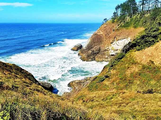 Golden cliffs drop dramatically into turquoise waves that crash and foam against ancient rocks below the windswept headland.
