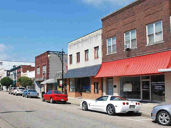 Red awnings pop against brick storefronts on this quiet main street where a Corvette looks right at home.