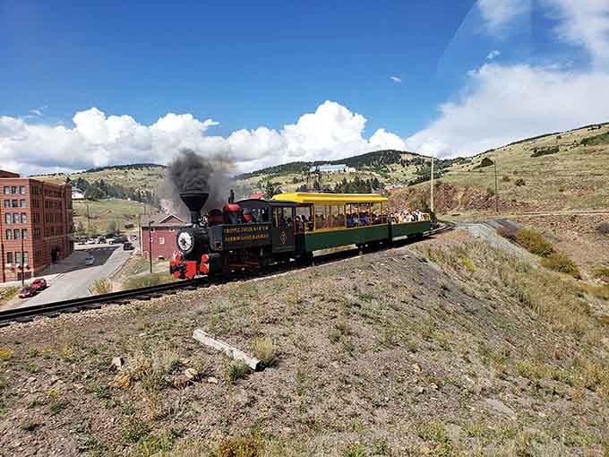That colorful little engine puffing past old mining structures proves good things really do come in small, cheerful packages.
