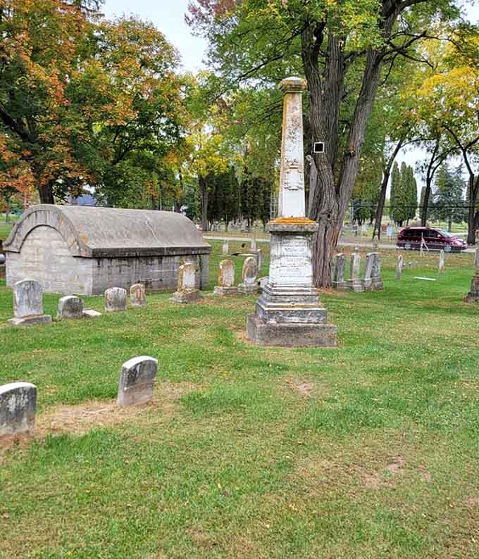 Weathered monuments stand sentinel among autumn leaves, marking stories that echo through time like whispers on the wind.